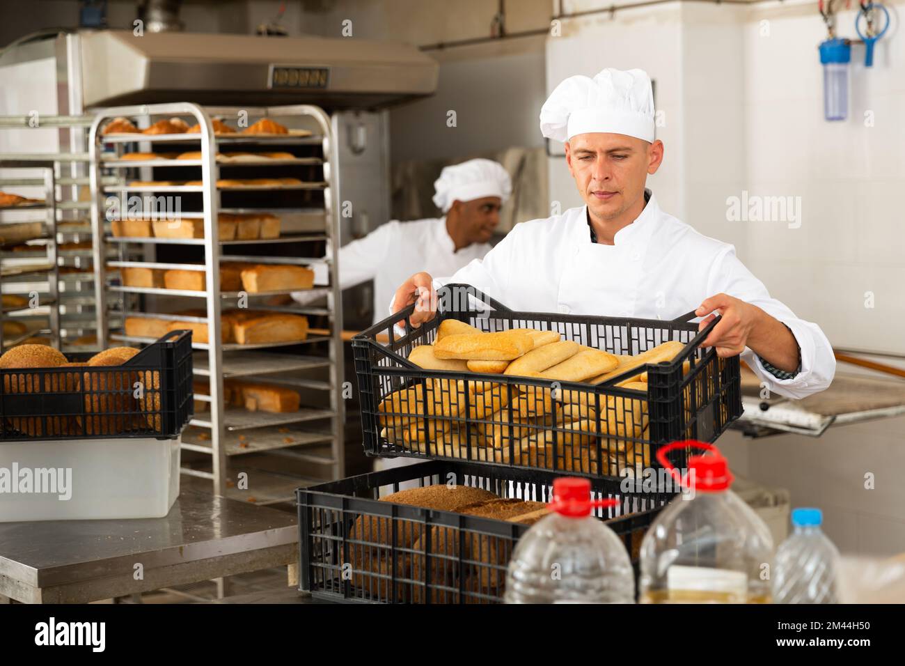 Positive bakery worker lays fresh bread Stock Photo - Alamy