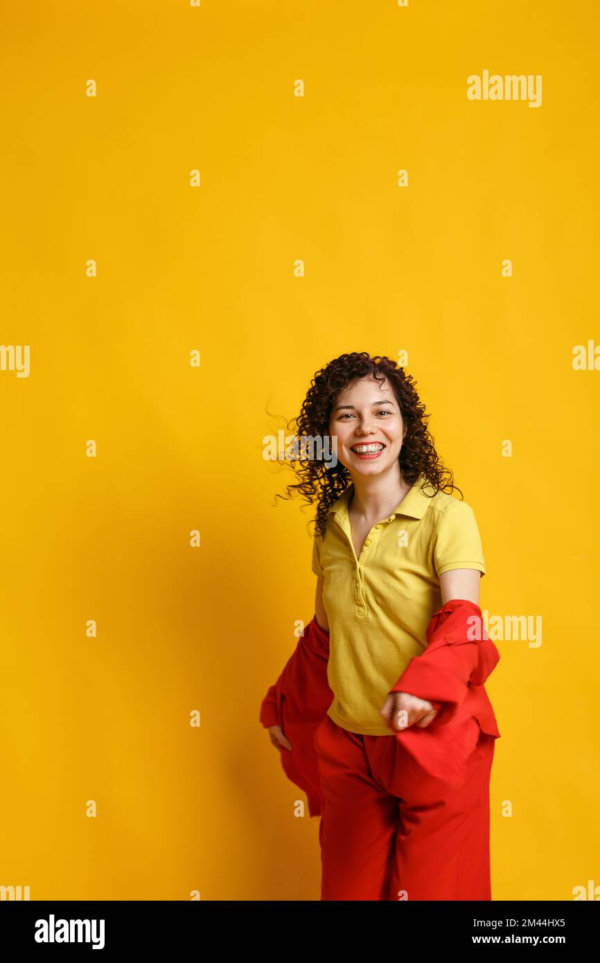 Curly cute girl laughs and jumps. Studio portrait of a woman on a ...
