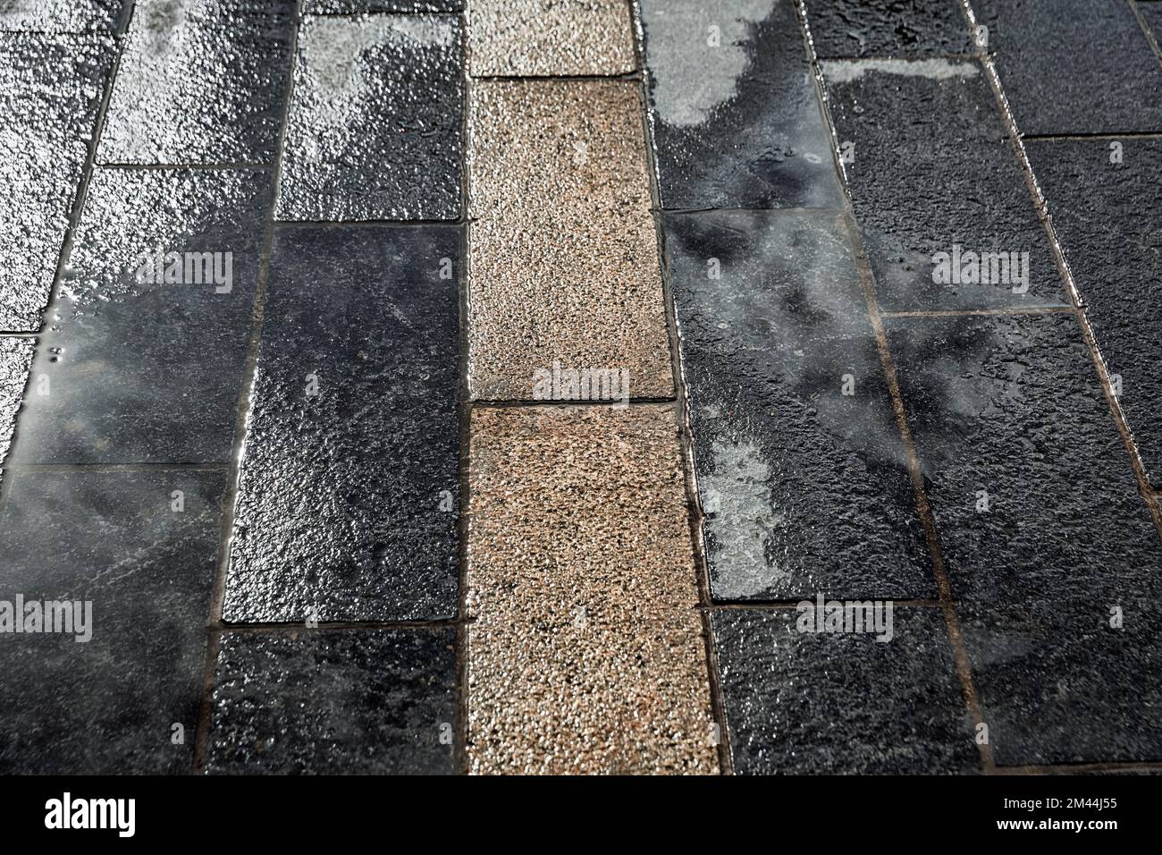 Rain-soaked footpath, stone tiles glistening in the sun, changeable ...