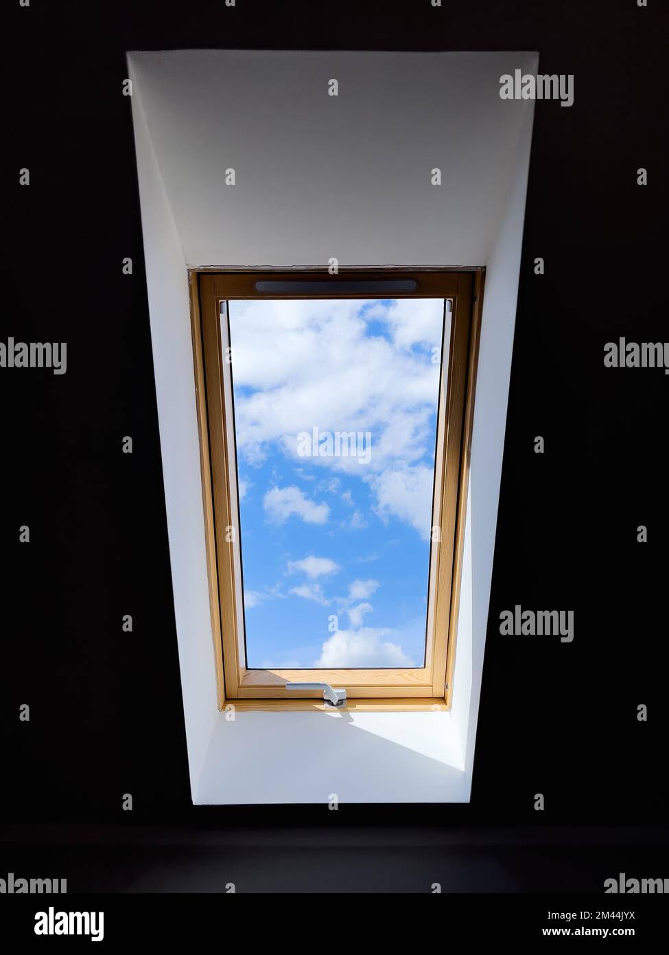 A vertical of the bright, cloudy sky seen from a ceiling window in a ...