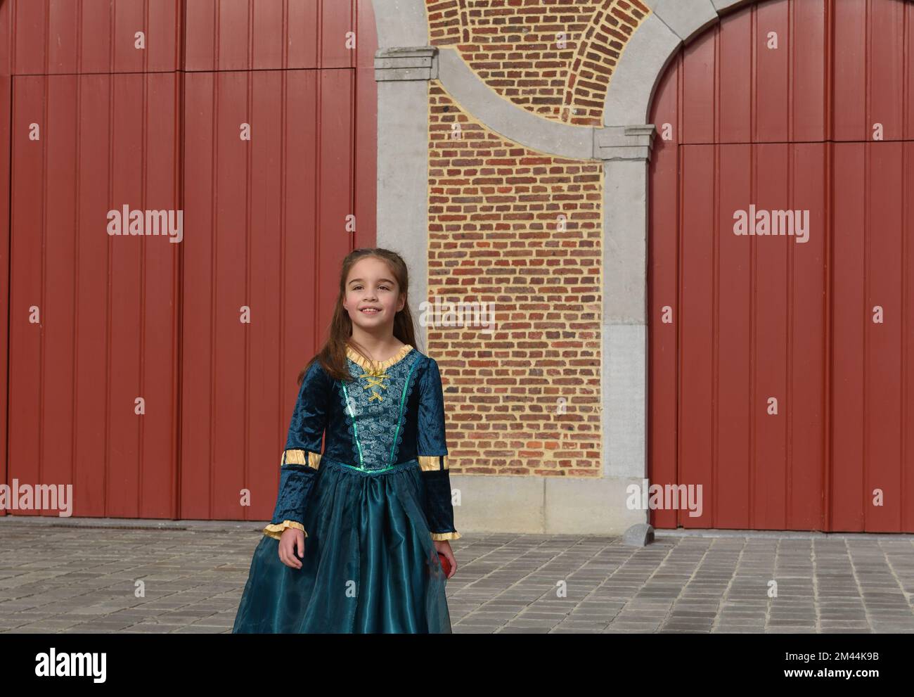 A young girl dressed in medieval garb stands before a castle Stock ...
