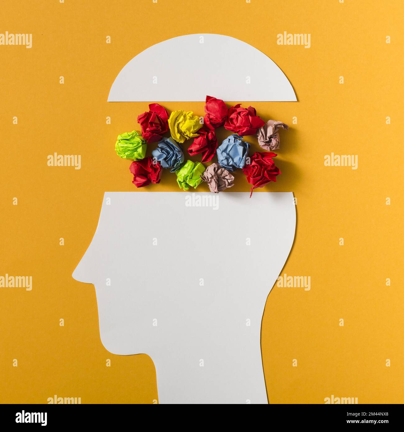 Colorful crumpled paper ball inside the paper cut out head on yellow ...