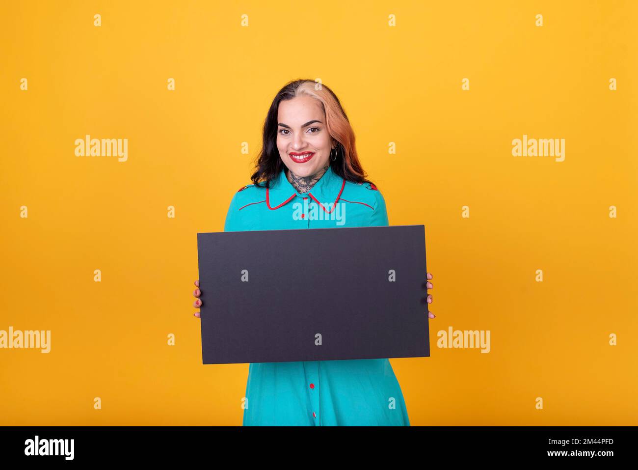 Beautiful woman holding a blank sign against a yellow background Stock ...