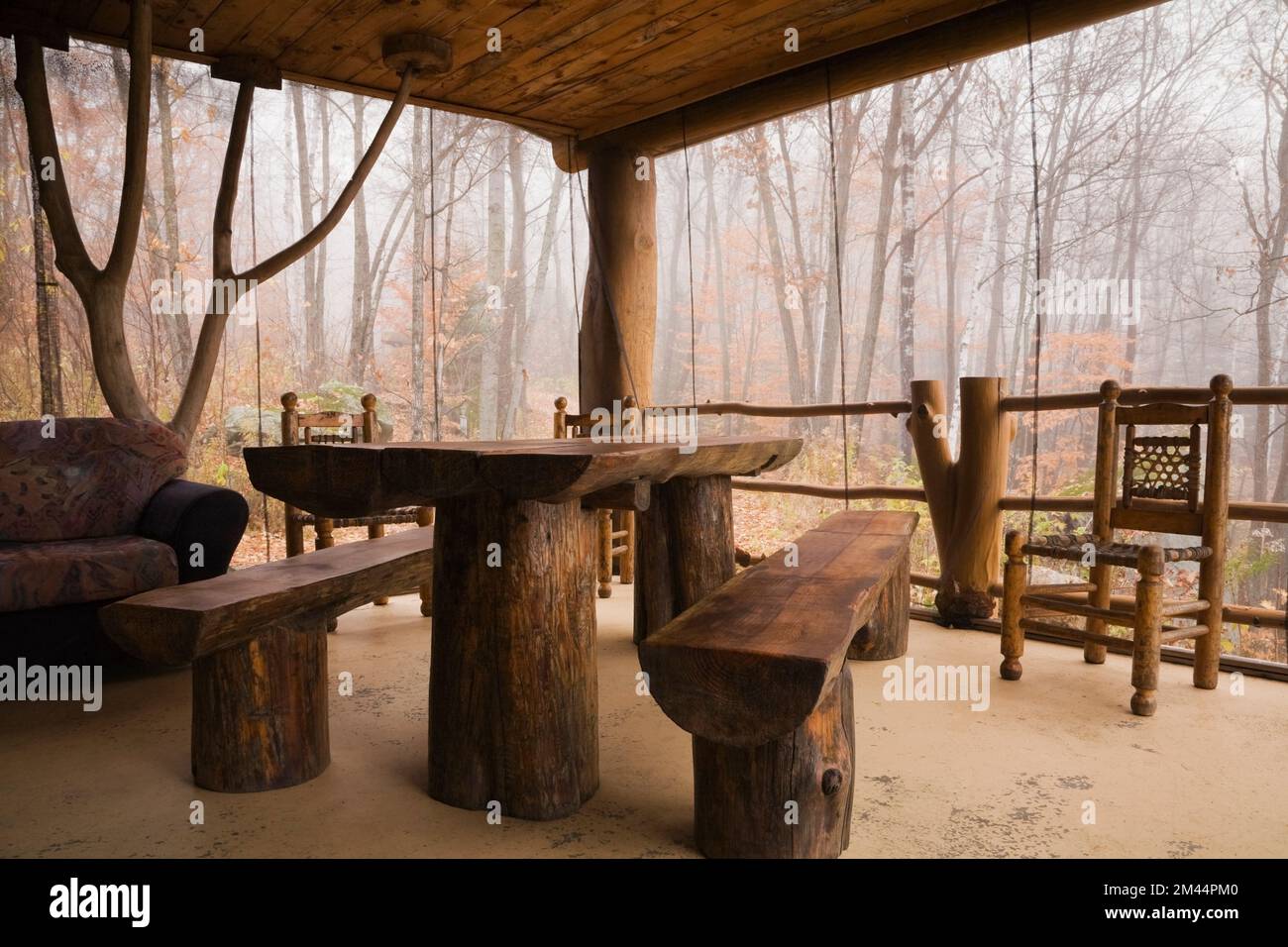 Stained and varnished split log dining table and benches in sunroom ...