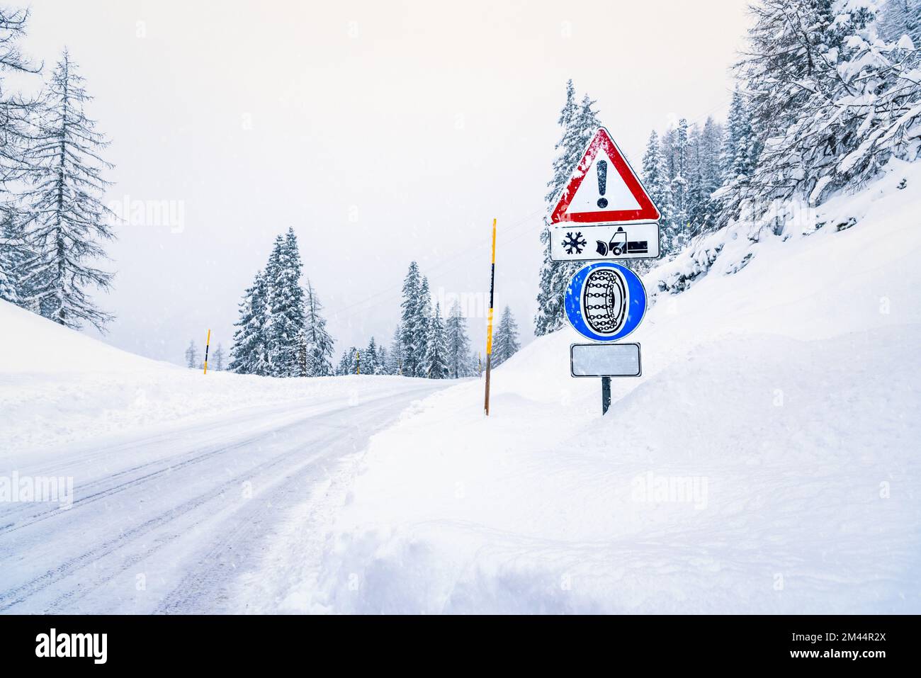 Warning sign and a tyre chains sign along a snowy mountain road during ...