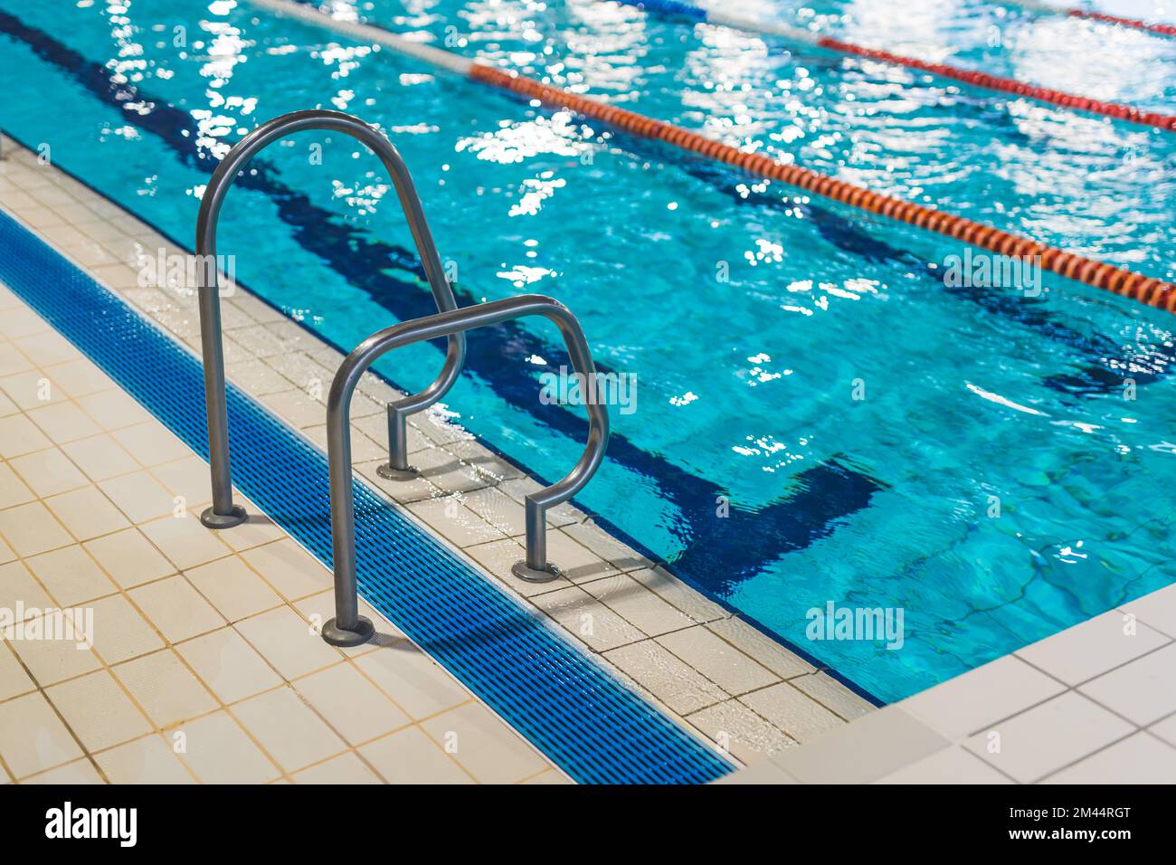 High angle shot of a metal swimming pool ladder with a pool lane in a ...