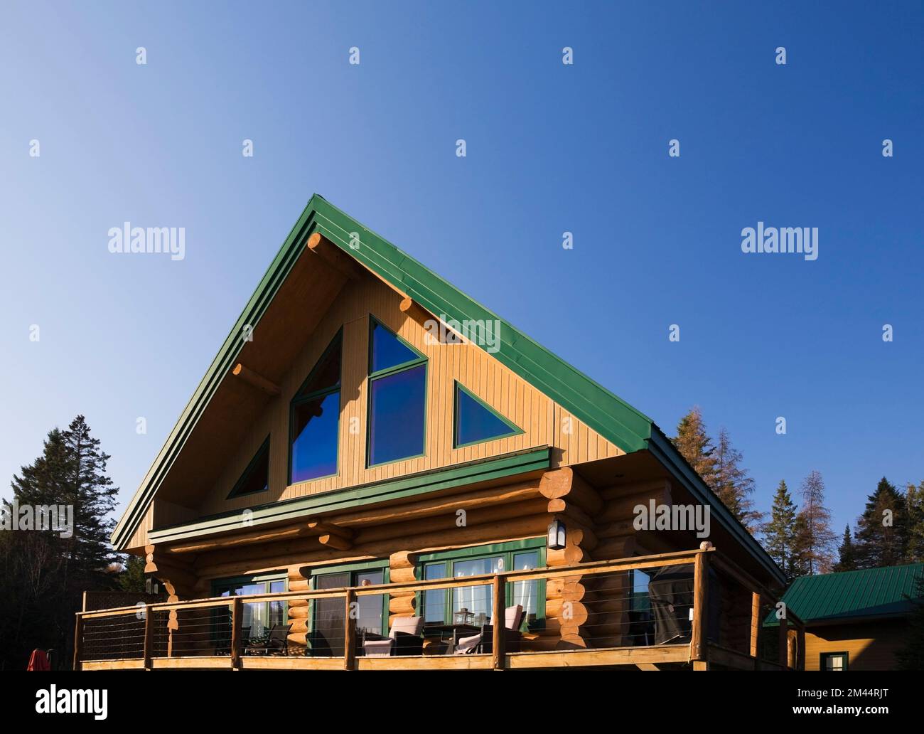 Back view of two story A-frame style log home with green trim in autumn ...