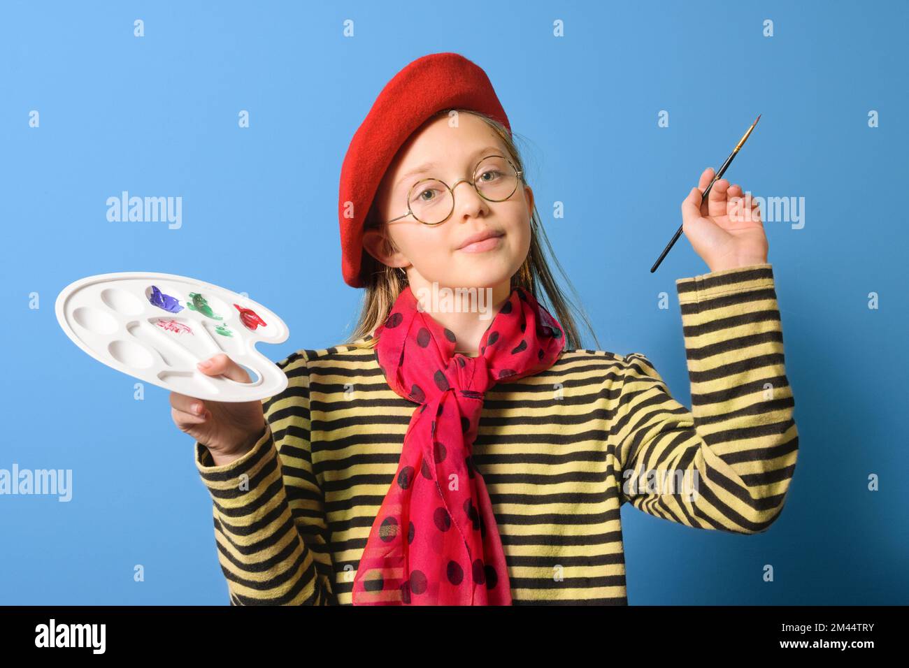 Young artist. A girl with a palette of colors in a bright red beret and ...