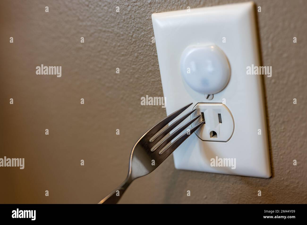Selective focus on edge of a metal fork about to be inserted into an ...