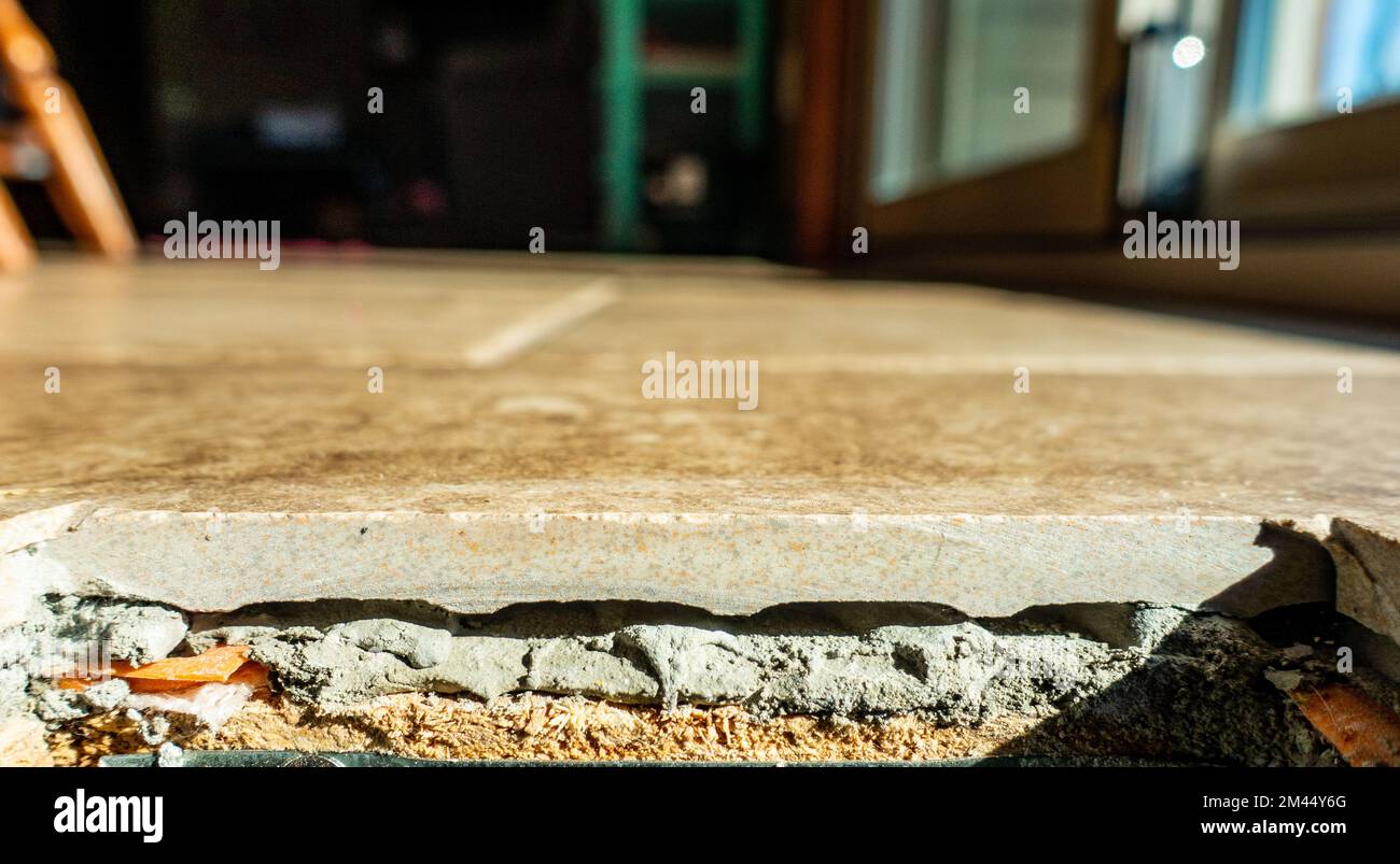Side view of a kitchen flooring cutout with tile, grout, and plywood ...