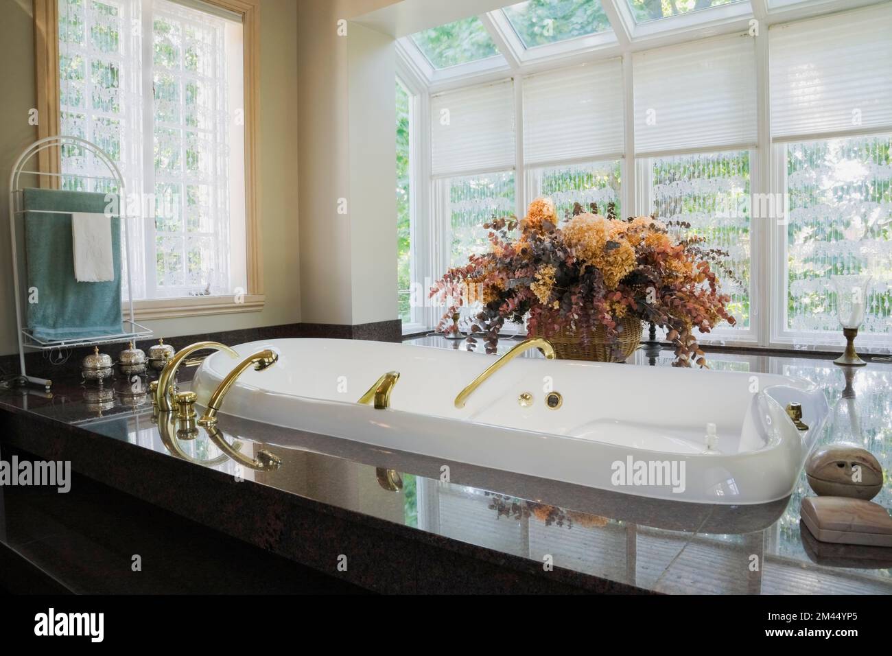 White Jacuzzi bathtub with brass faucets encased in granite base in ...