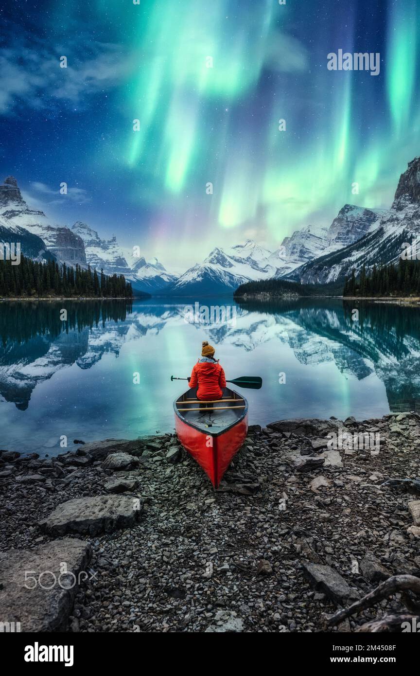 Beautiful aurora borealis over spirit island with female traveler on ...
