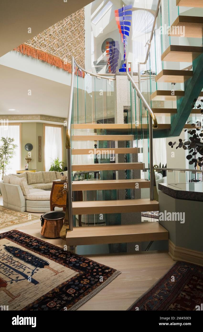 Glass, metal and wood twisting staircase inside luxuriously decorated ...