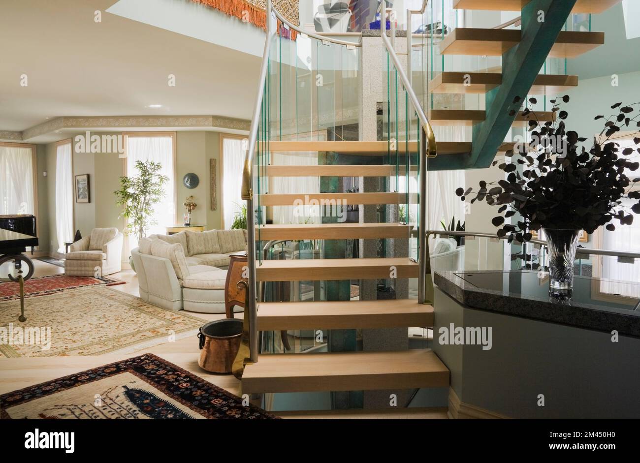 Glass, metal and wood twisting staircase inside luxuriously decorated ...