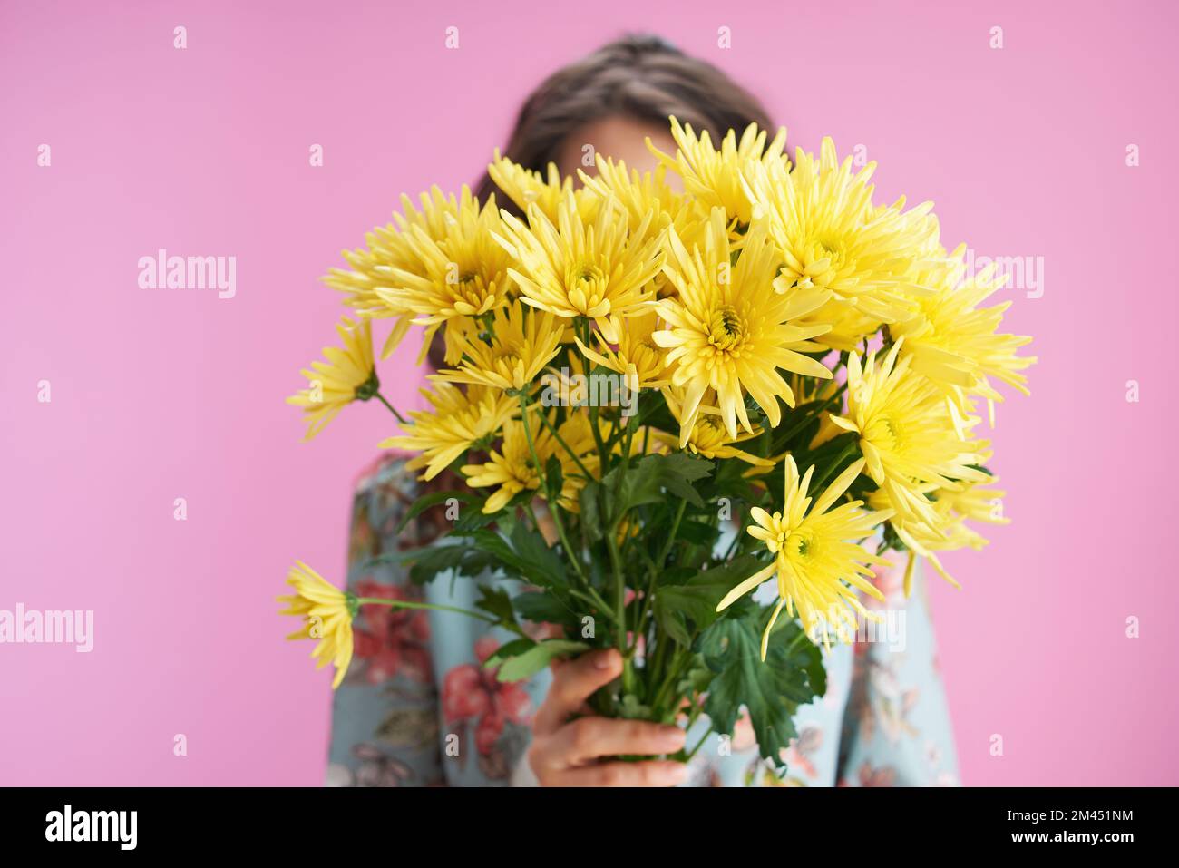elegant woman in floral dress hiding behind yellow chrysanthemums ...