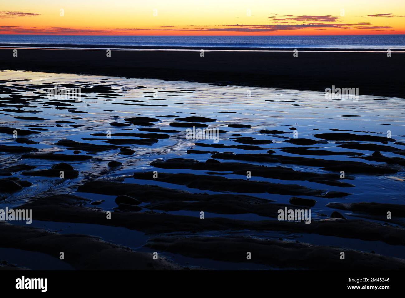 Water Ripples in the beach sand reflect the sunrise along the coast ...