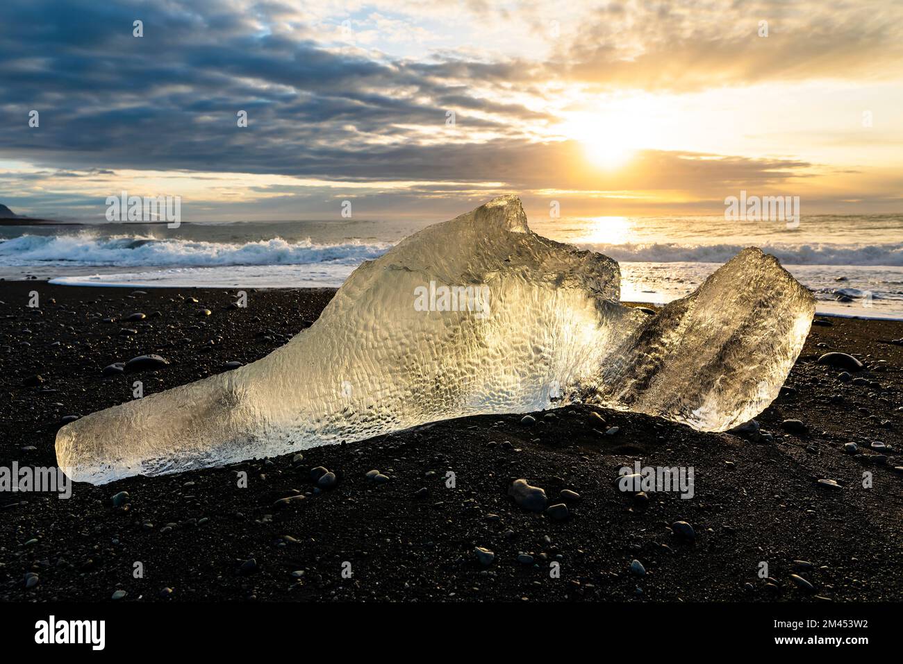 Magical backlit iceberg lying on the black sand of Breiðamerkursandur ...