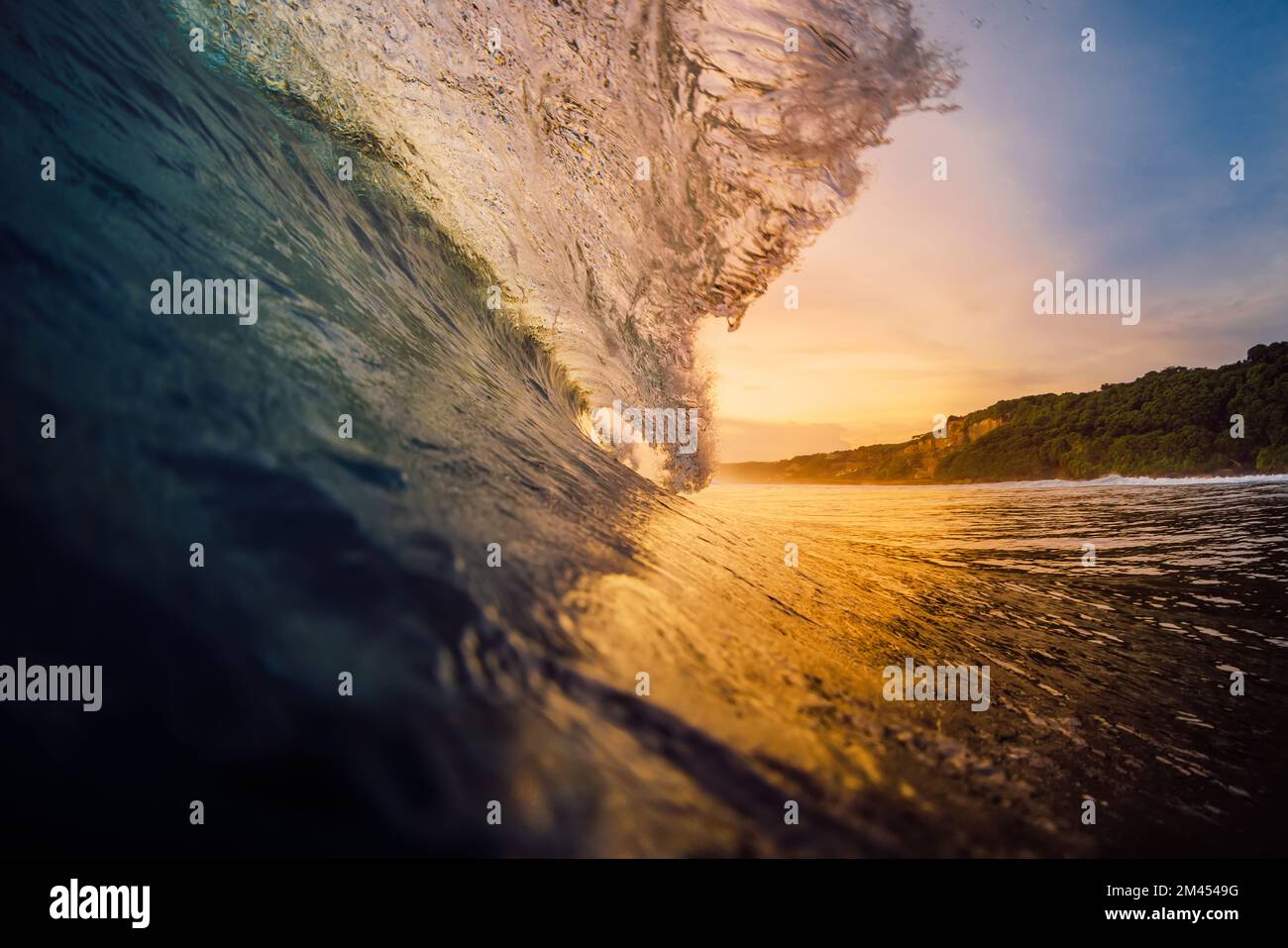 Surfing wave breaking in ocean with warm sunset tones Stock Photo - Alamy
