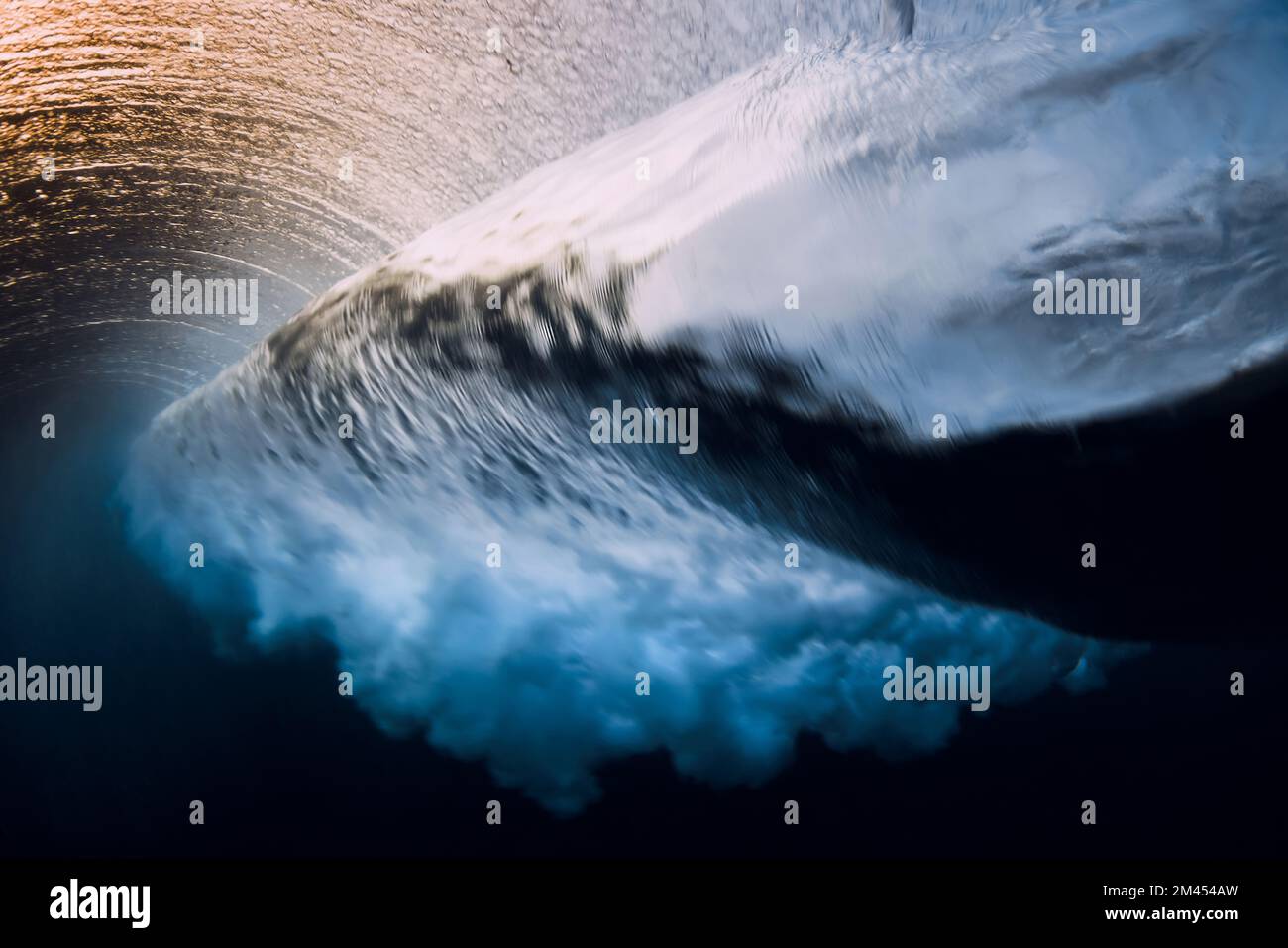 Barrel wave crashing in ocean with sunset or sunrise light. Underwater ...