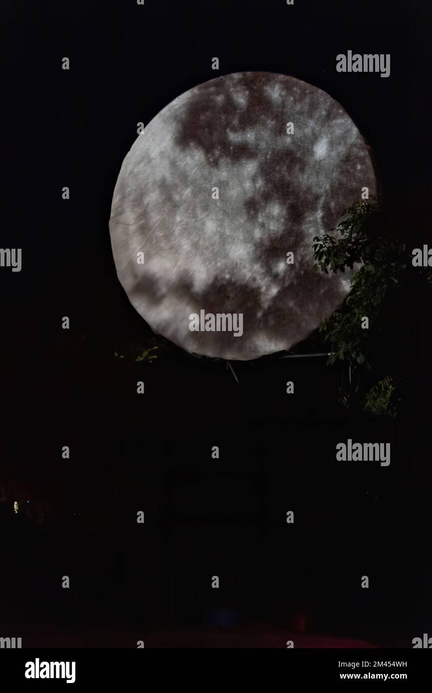 full moon in the background, in front a chandelier of warm light ...