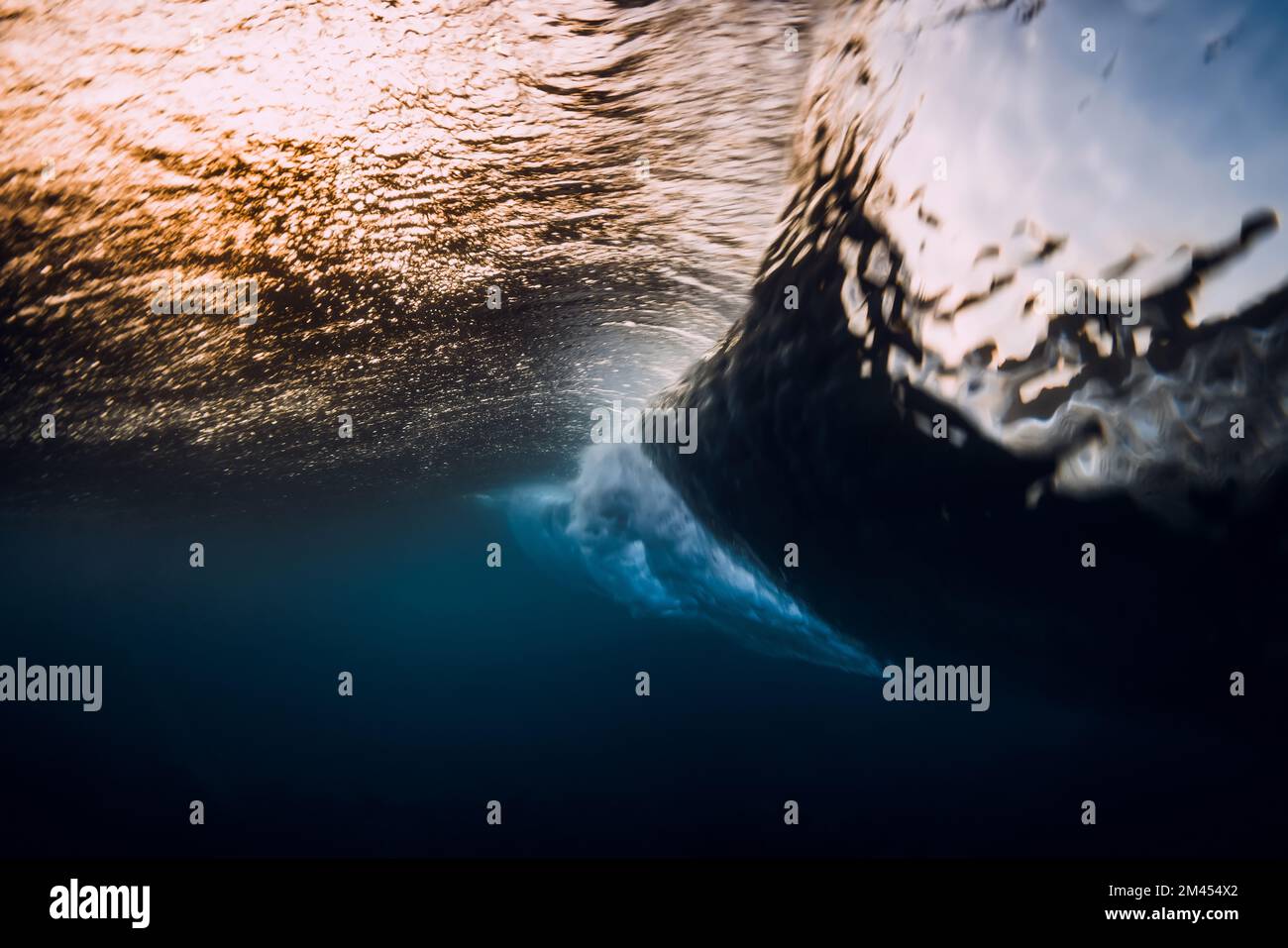 Barrel wave crashing in ocean with sunset or sunrise light. Underwater ...