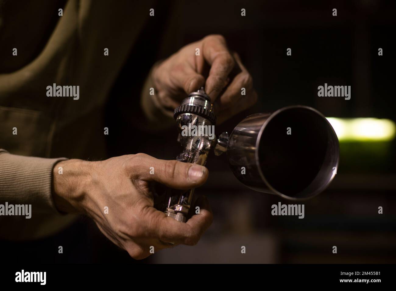 Hands hold bullet. Paint sprayer. Chrome-plated object. Spray tool ...