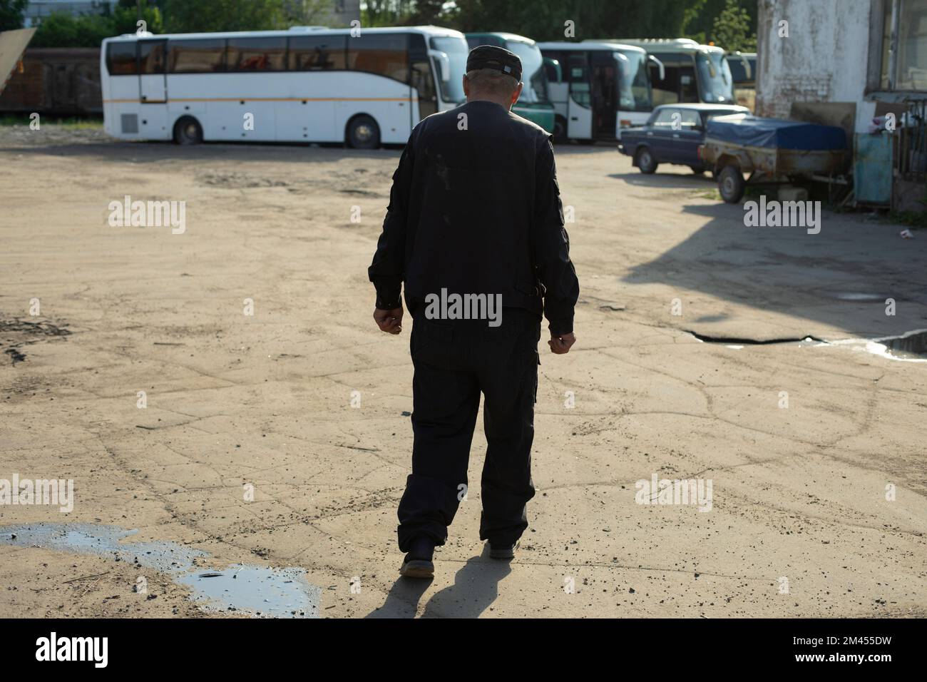 Man walks through industrial area. Bus parking. Parking guard. Man in ...