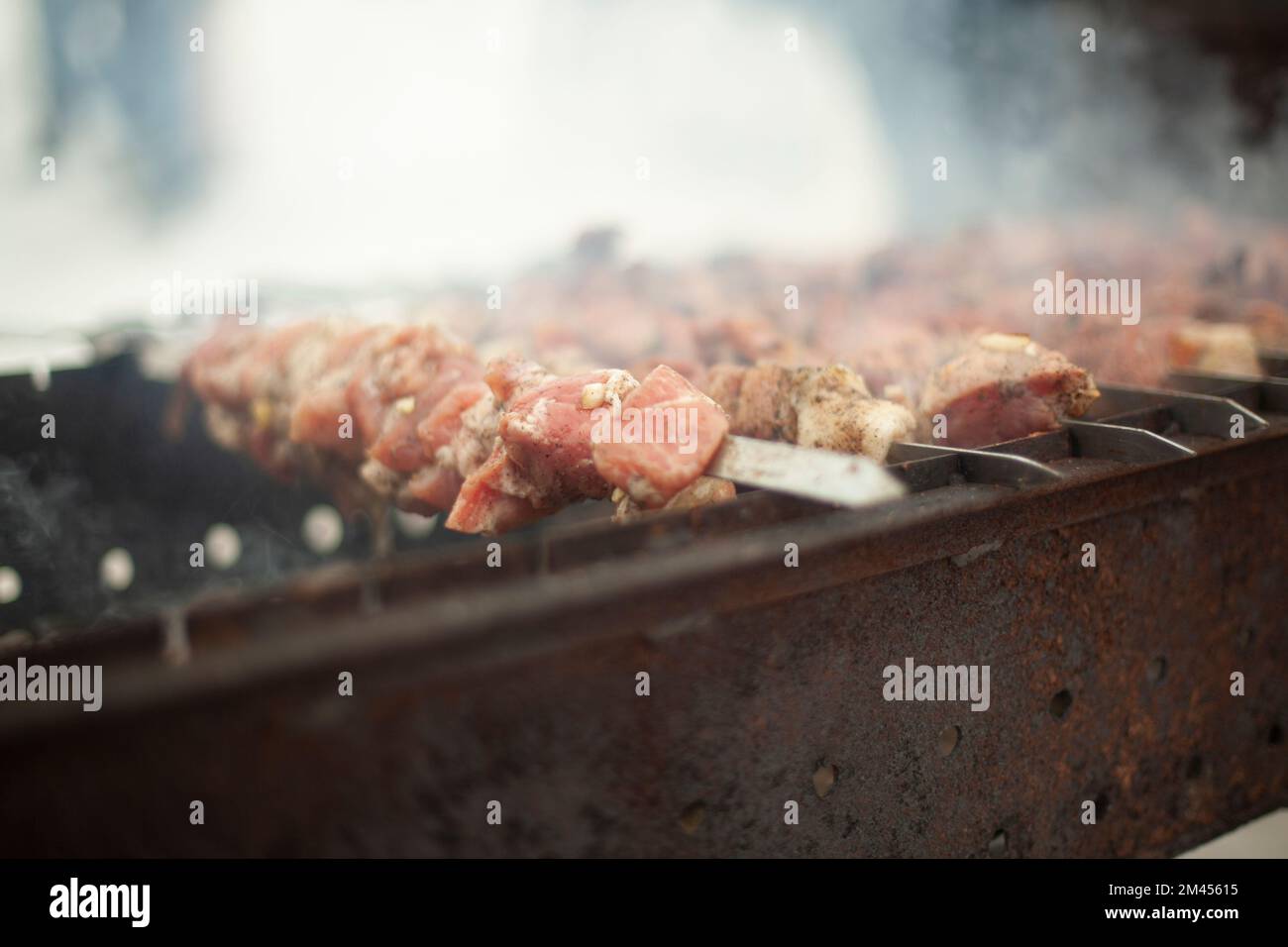 Frying meat on fire. Meat strung on blade. Outdoor kitchen. Fatty food ...