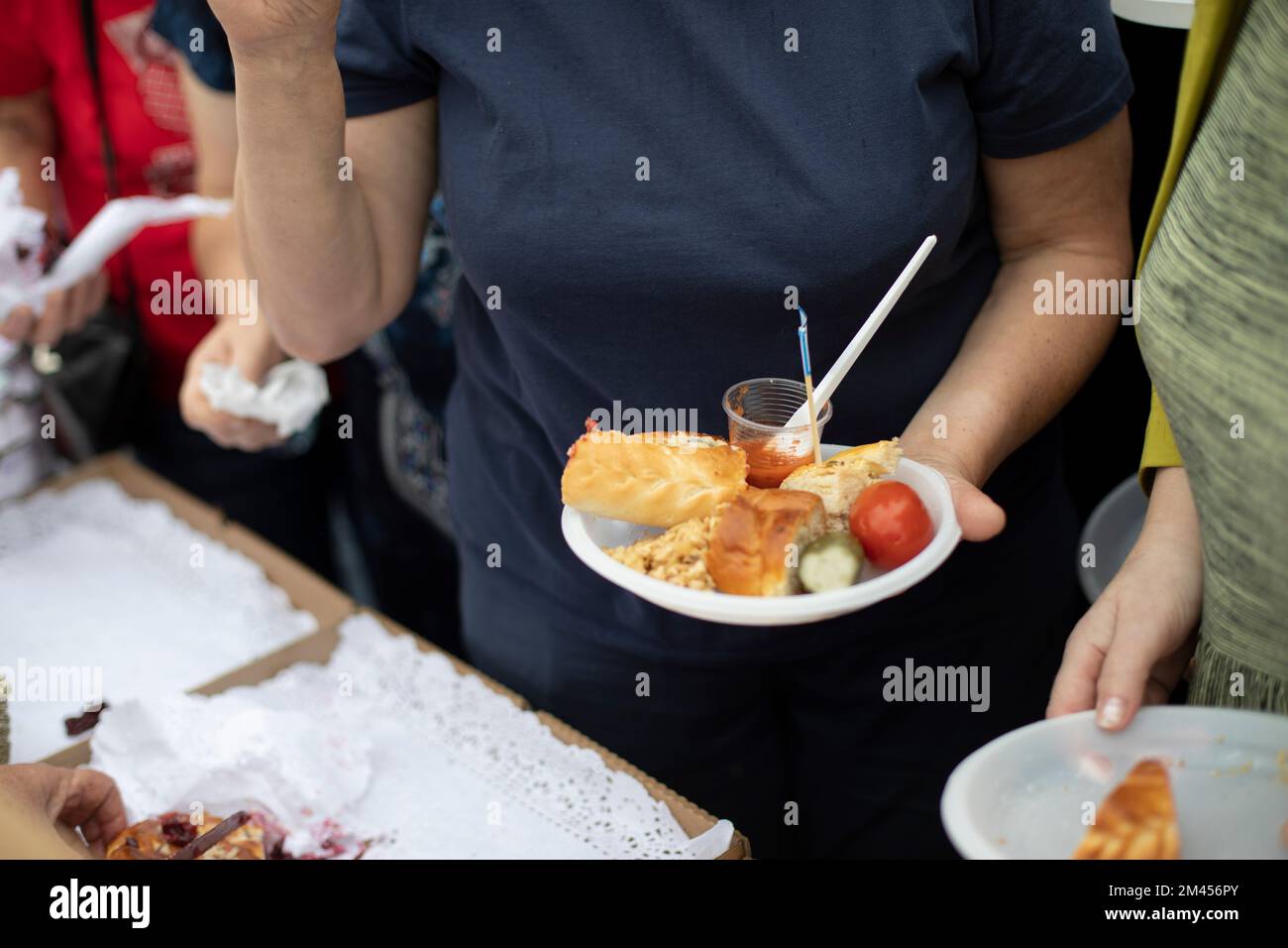 Food in plate in your hand. Man eating on street. Delicious food. Queue ...