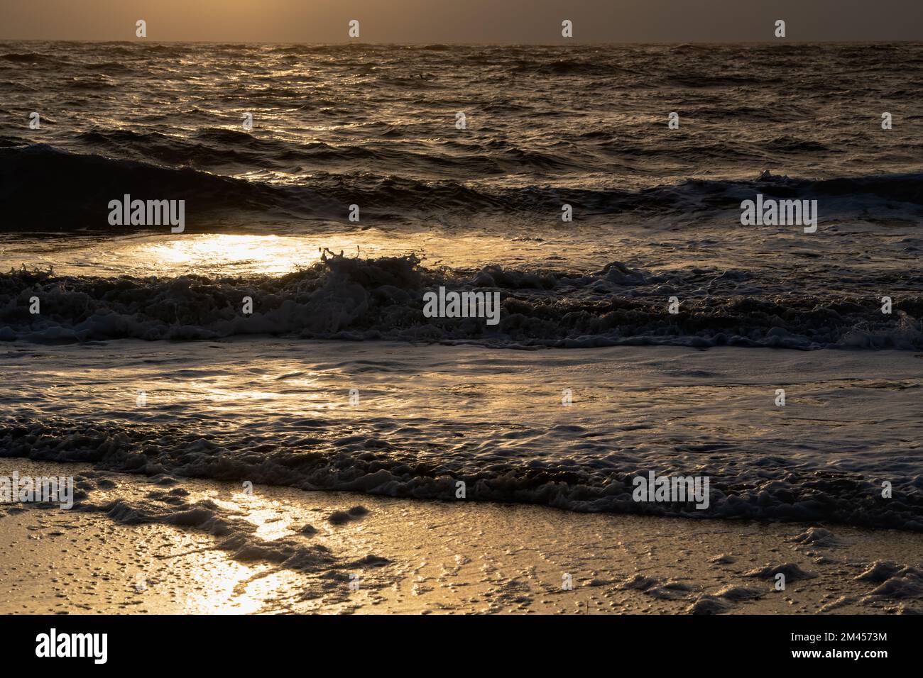 Sun glinting on the ocean water and the wet sand in early morning Stock ...