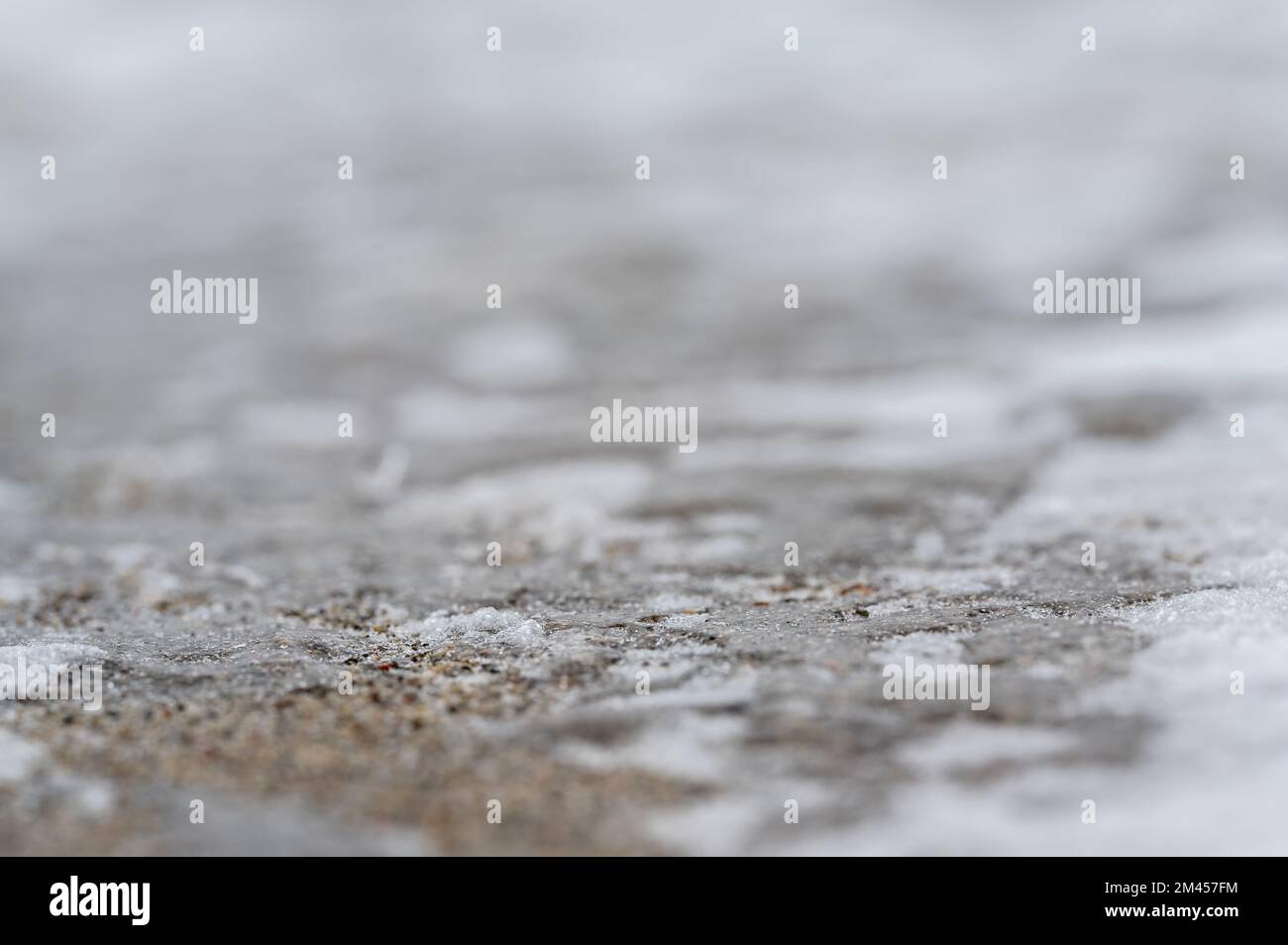 macro ground level closeup view of rock salt ice-melt on concrete with ...