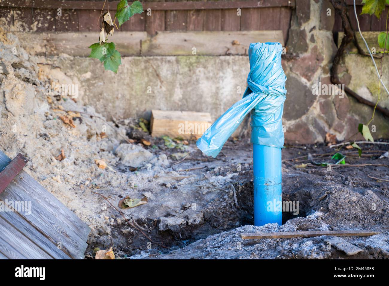 The blue pipe of a freshly drilled well sticks out of the ground close ...