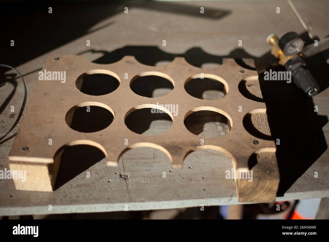 Round holes in board. Rugged board on table. Item in garage. Material ...