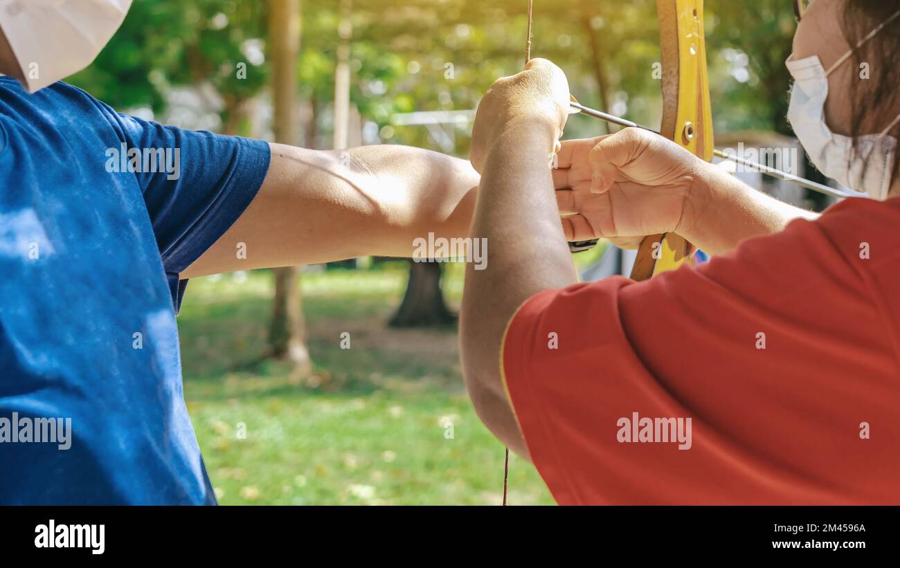 Female teacher teaches student to aim at goal. An archer teaching young ...