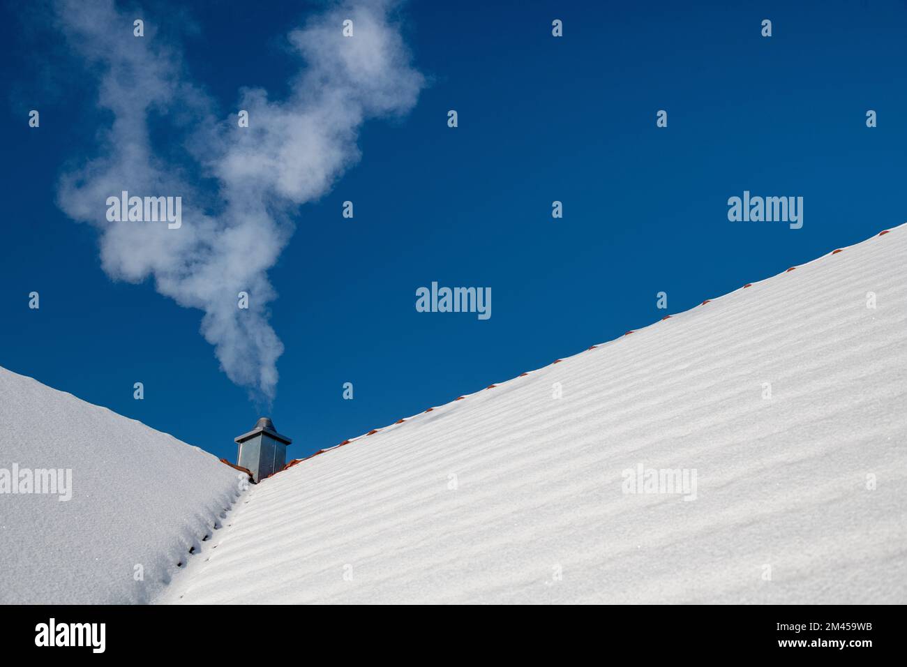 chimney smokes in the winter cold with a bright blue sky and sunshine ...