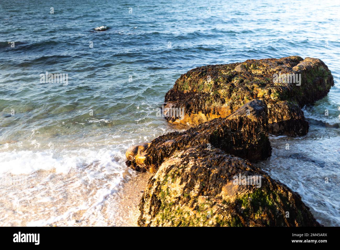 A view of weathered rocks in wavy blue sea Stock Photo - Alamy