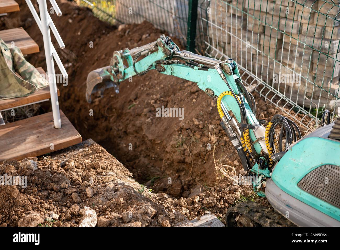 Mini excavator digs a trench to lay pipes. Close up of an excavator ...