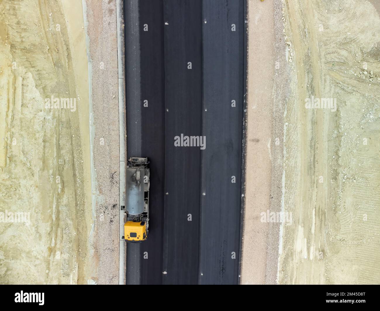 yellow truck pouring bitumen over a new road. Aerial drone shot. Road ...