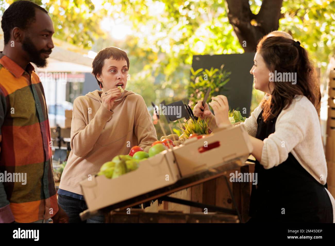 Multiracial couple tasting bio organic produce at farmers market ...