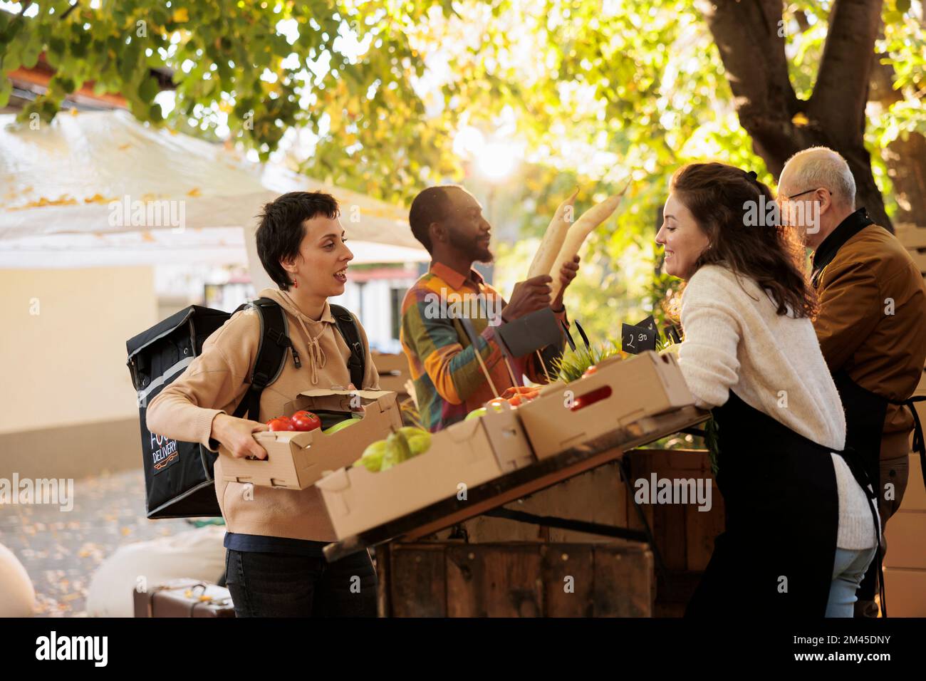 Cheerful courier and local stand owner talking about natural products ...