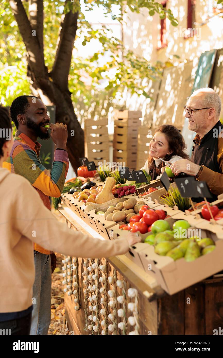 Young happy African guy tasting apple before purchasing while shopping ...