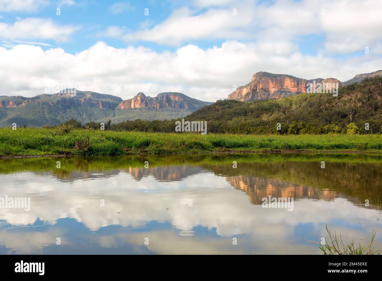 Steep cliffs of the Capertee canyon reflecting in water from the valley ...