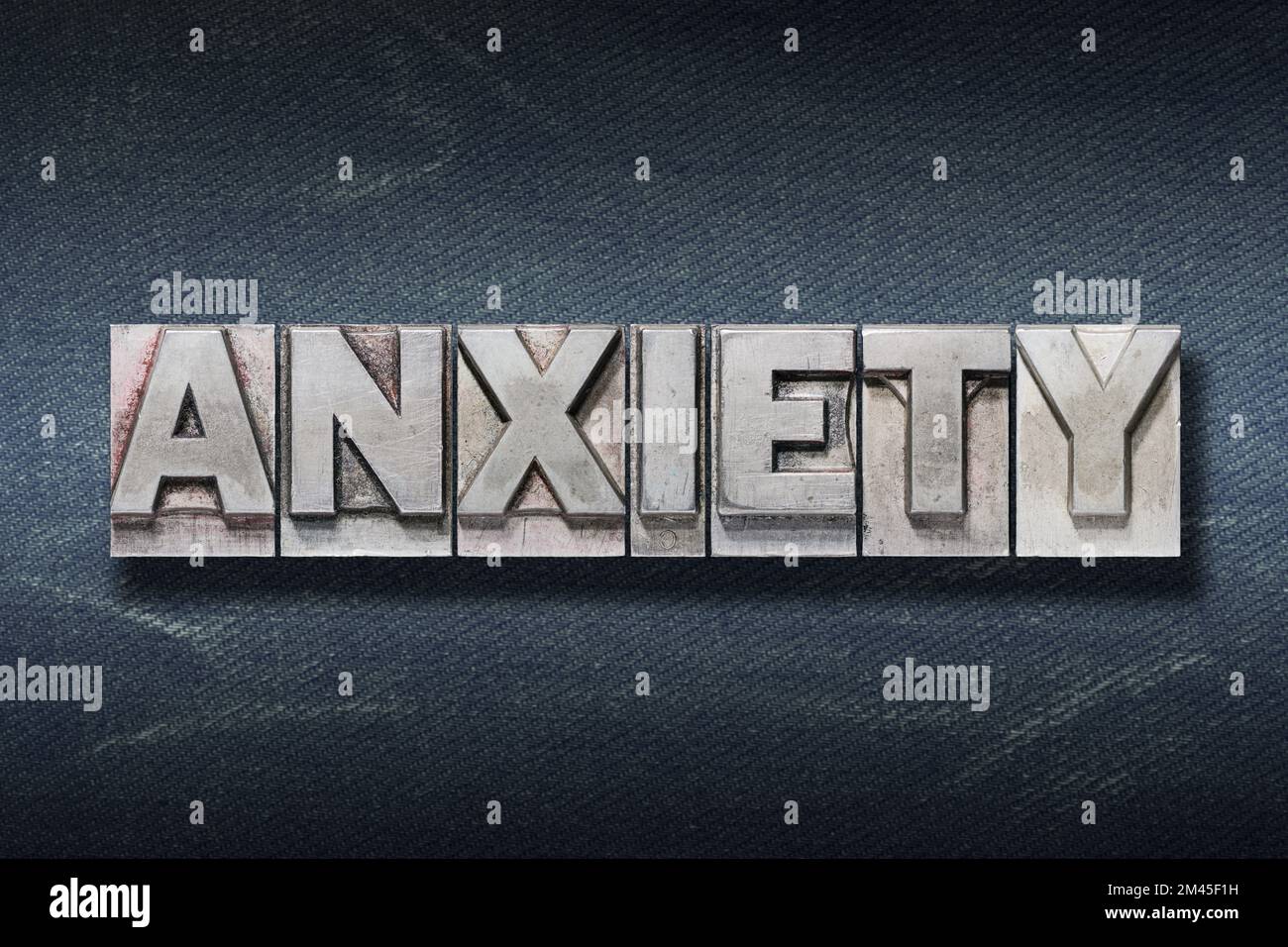 anxiety word made from metallic letterpress on dark jeans background ...
