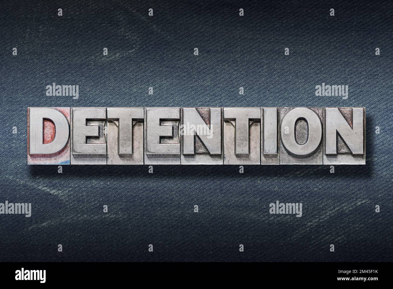 detention word made from metallic letterpress on dark jeans background ...