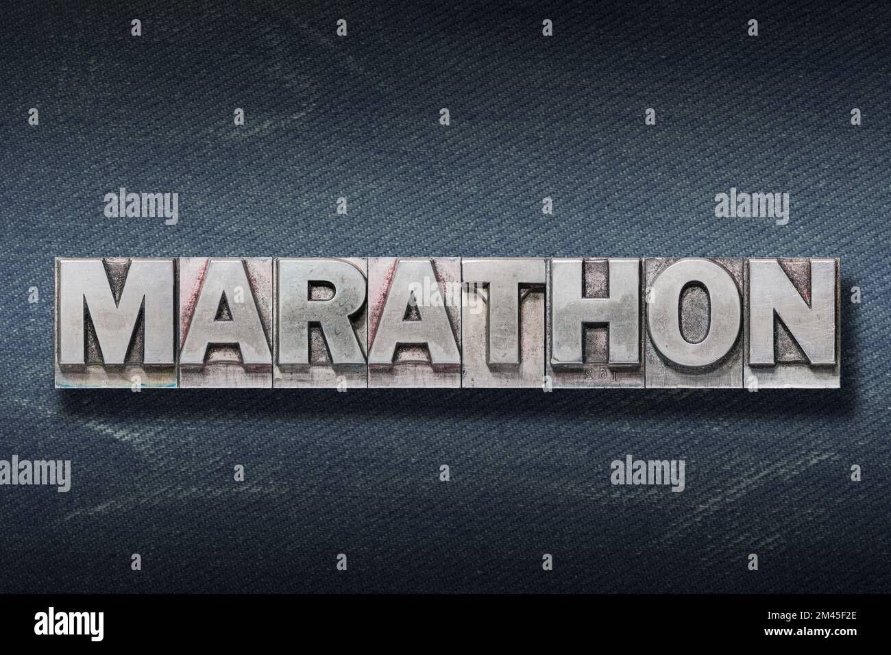 marathon word made from metallic letterpress on dark jeans background ...