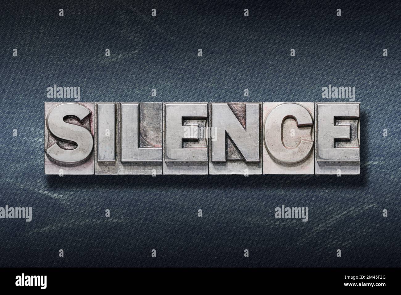 silence word made from metallic letterpress on dark jeans background ...