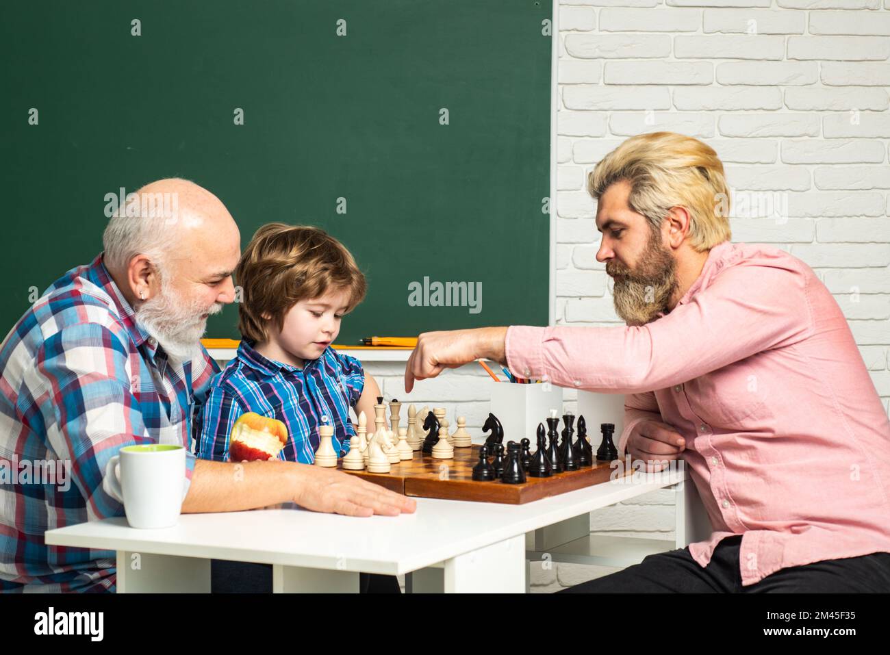 Fathers day. Grandfather father and sonplaying chess. Grandpa teaching ...