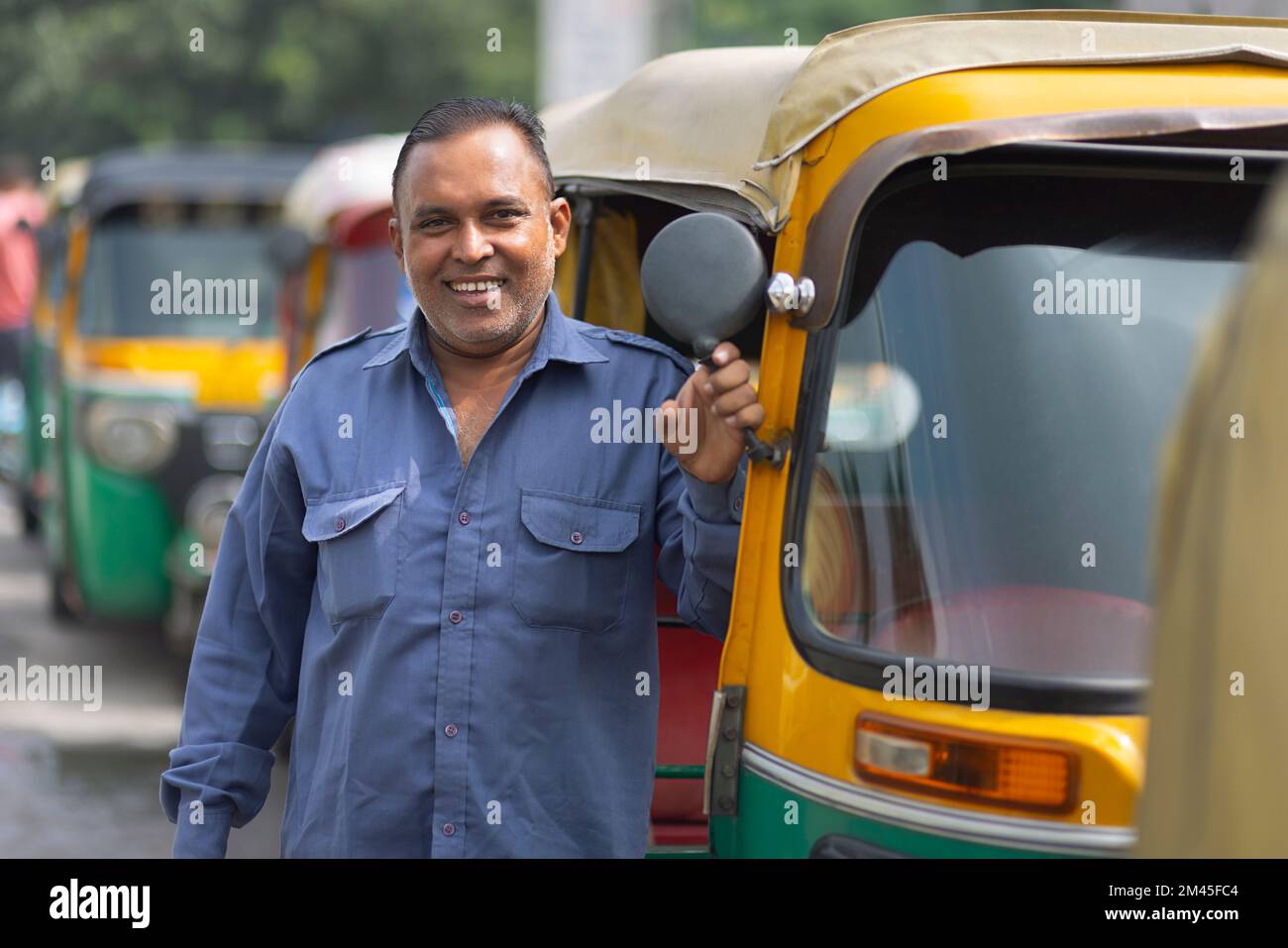 Portrait of a smiling auto rickshaw driver standing on road Stock Photo ...