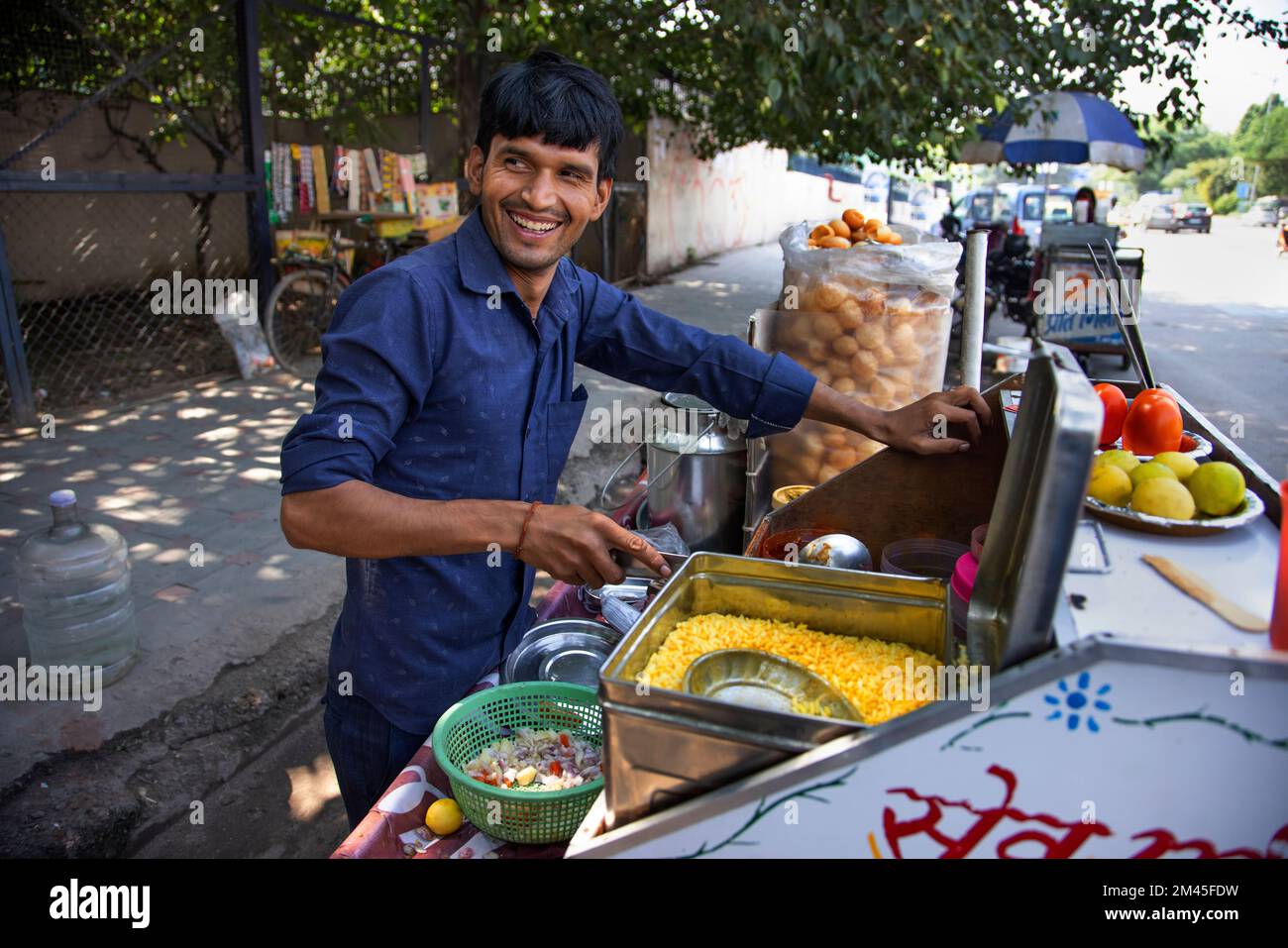 Portrait of a happy street vendor preparing ingredients at his stall ...