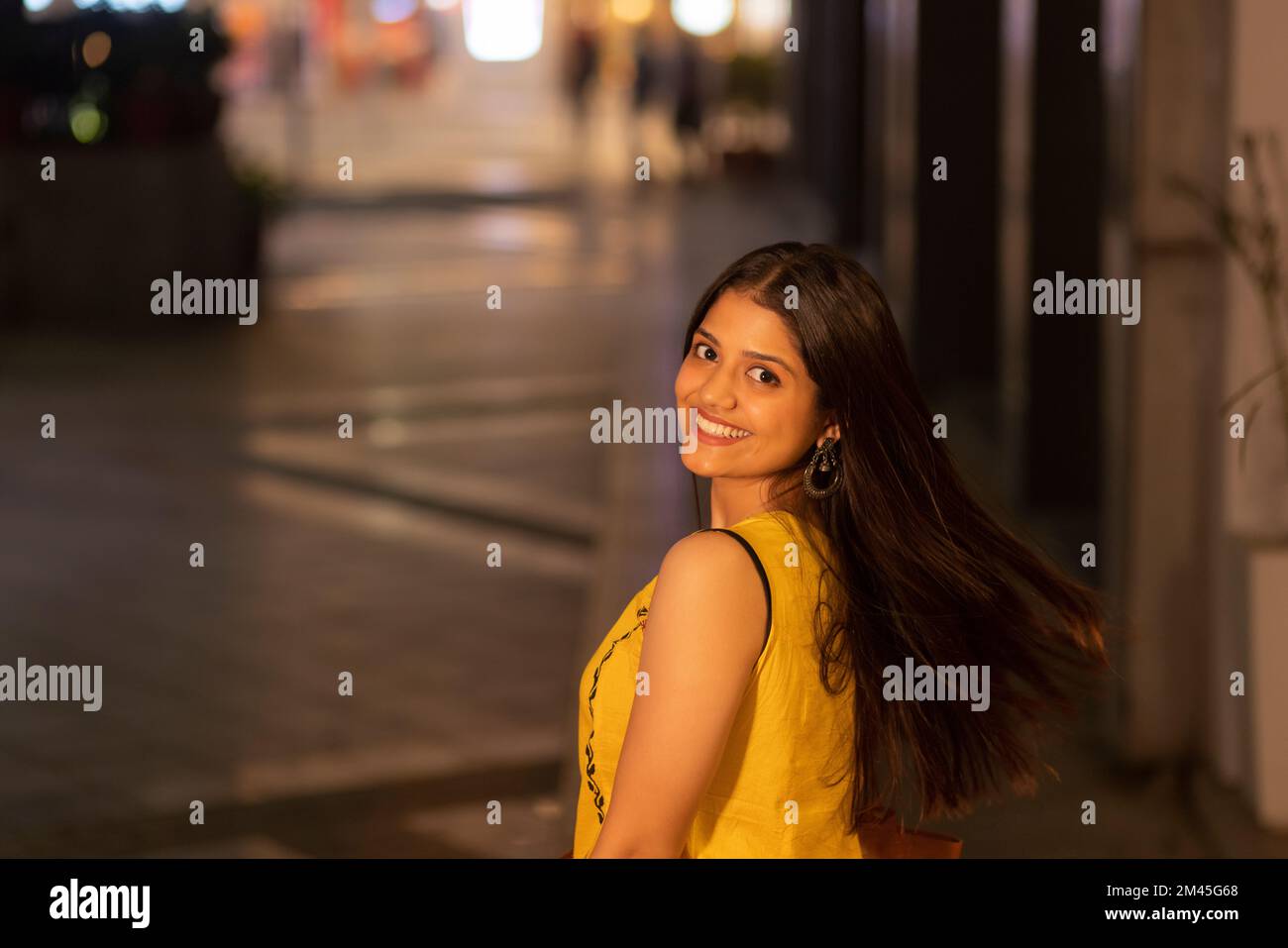 Woman looking back at camera with smile while walking on street Stock ...